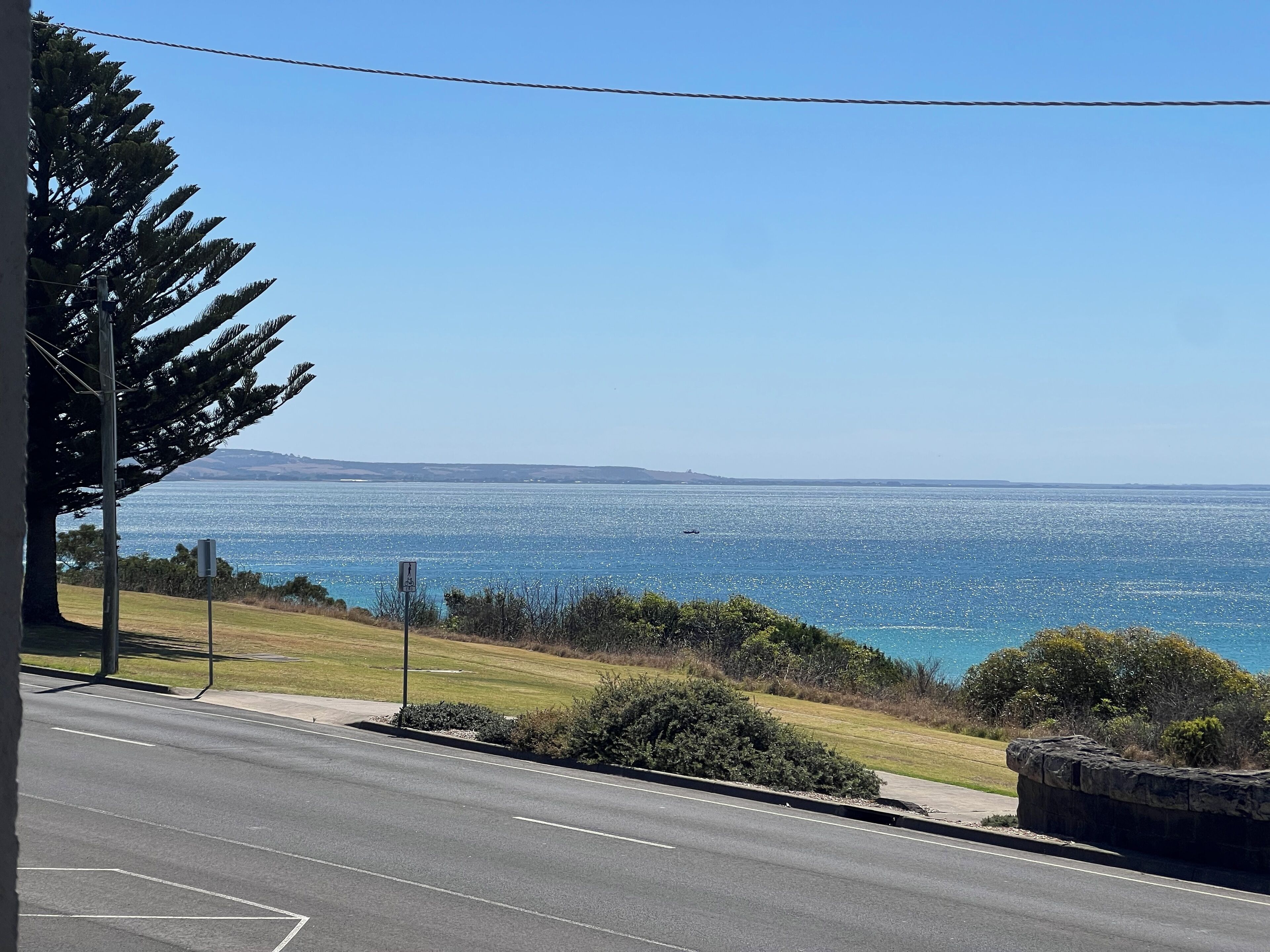 Uma estrada costeira com vista ampla para o mar e terra ao longe.