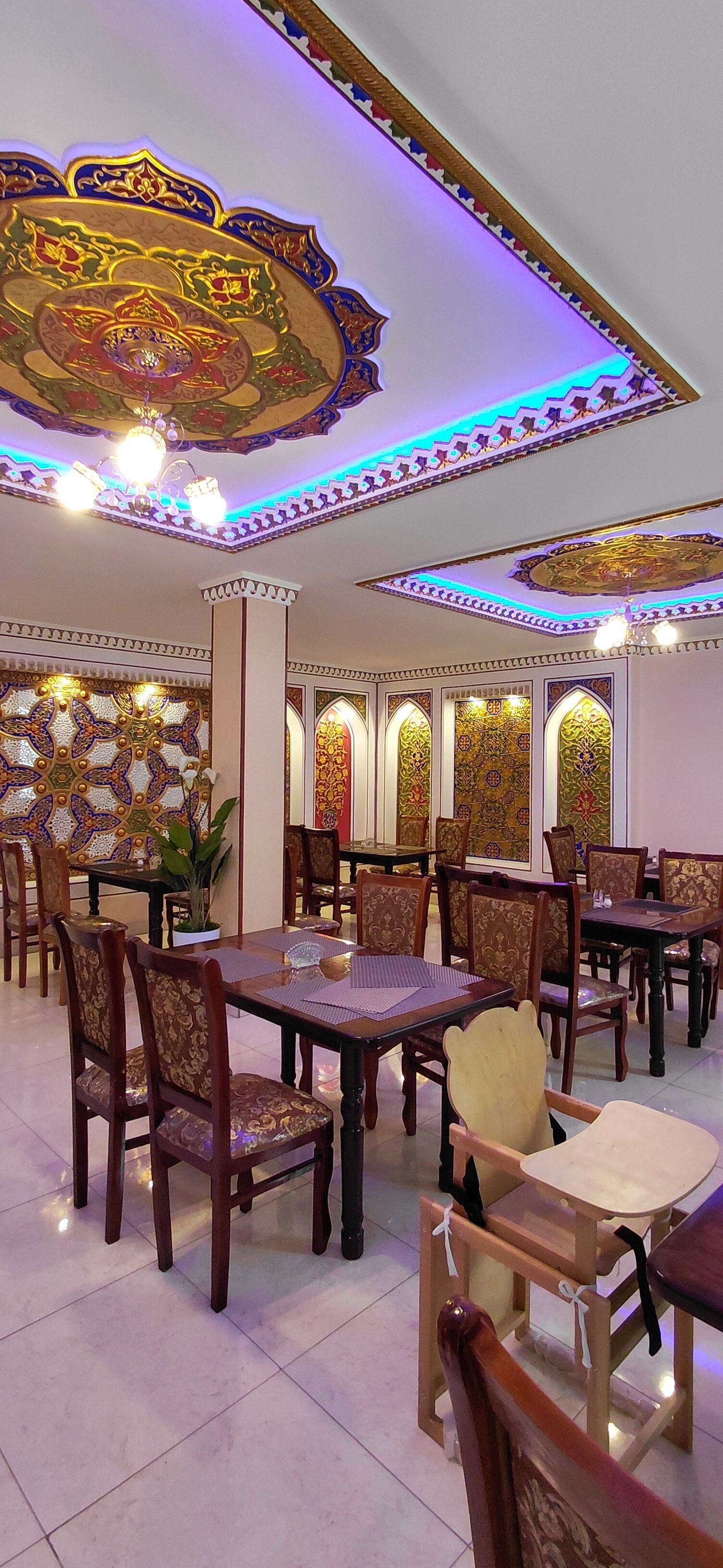 Restaurante com design de teto ornamentado, paredes padronizadas e mobiliário de madeira tradicional.