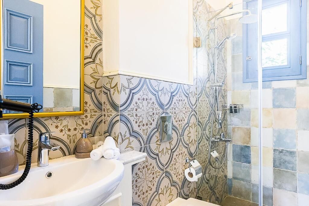 Casa de banho com lavatório, espelho e chuveiro.