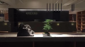 Uma mesa de recepção com design moderno, um vaso de planta e uma escultura.