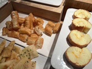 Uma bandeja com diversos alimentos, incluindo doces fritos e fatias de pão.