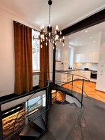 Um interior moderno com escada, luminária de cristal e área de cozinha.