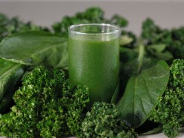 Um copo de suco verde envolto em folhas frescas de couve.
