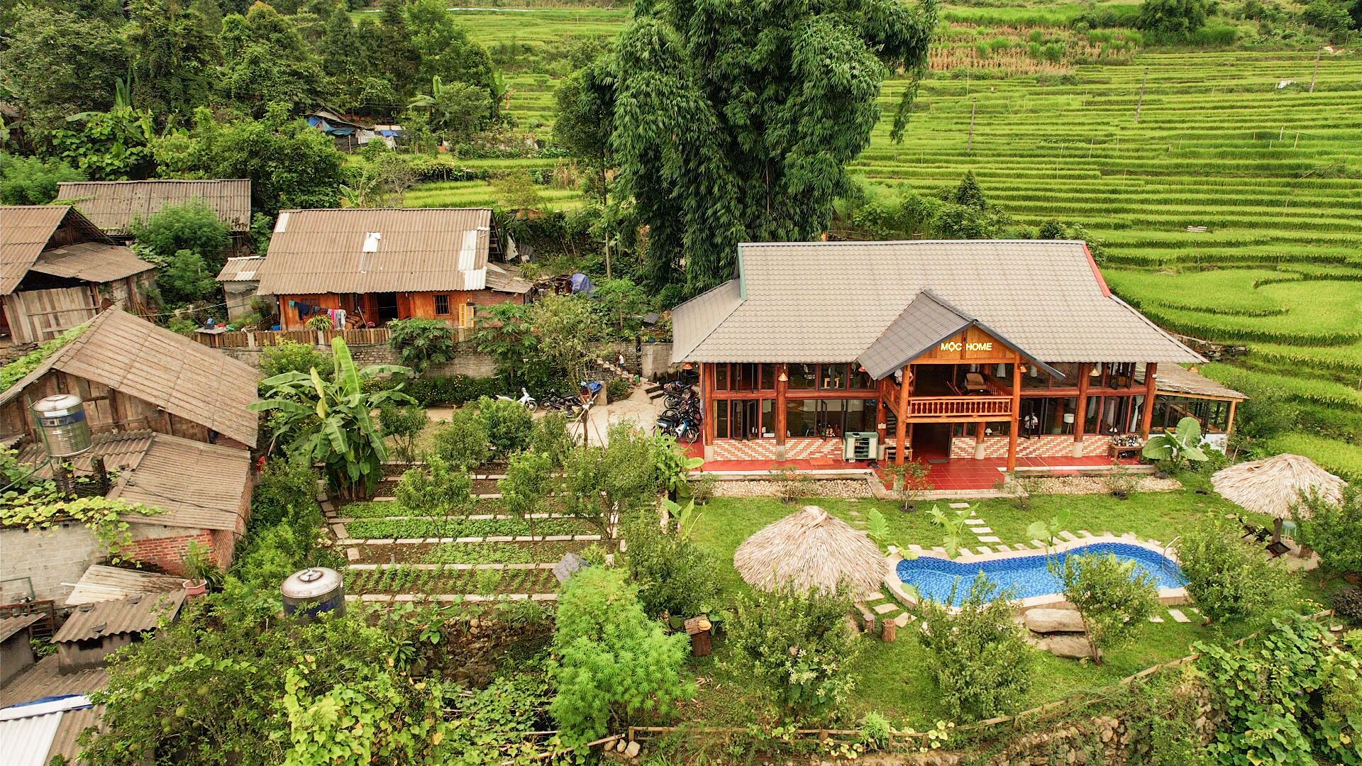 Uma casa grande com piscina, rodeada por vegetação exuberante e campos em socalcos.