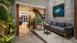 Interior moderno com parede de tijolos cinza, escada, sofá cinza e uma janela ampla.