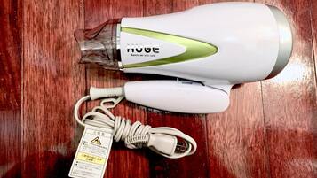 Secador de cabelo com fio elétrico e etiqueta de advertência sobre uma superfície de madeira.