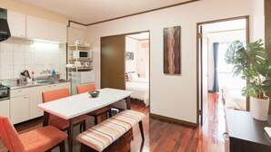 Uma cozinha compacta com armários brancos, micro-ondas e um espaço de jantar com banco.