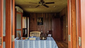 Quarto com cama, ventilador de teto, pintura e paredes de madeira.