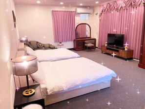 Quarto de hotel com duas camas, uma escrivaninha, uma cadeira, uma televisão e um ar condicionado.