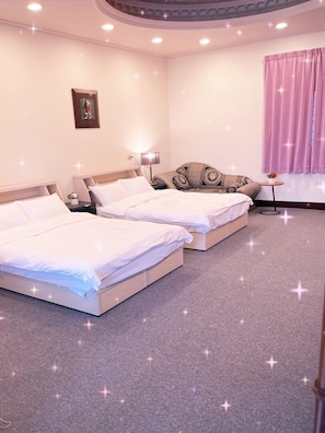 Quarto de hotel com duas camas, um sofá, uma mesa pequena e uma janela com cortinas.