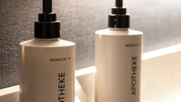 Dois frascos de loção vegetal Apotheke sobre um suporte.