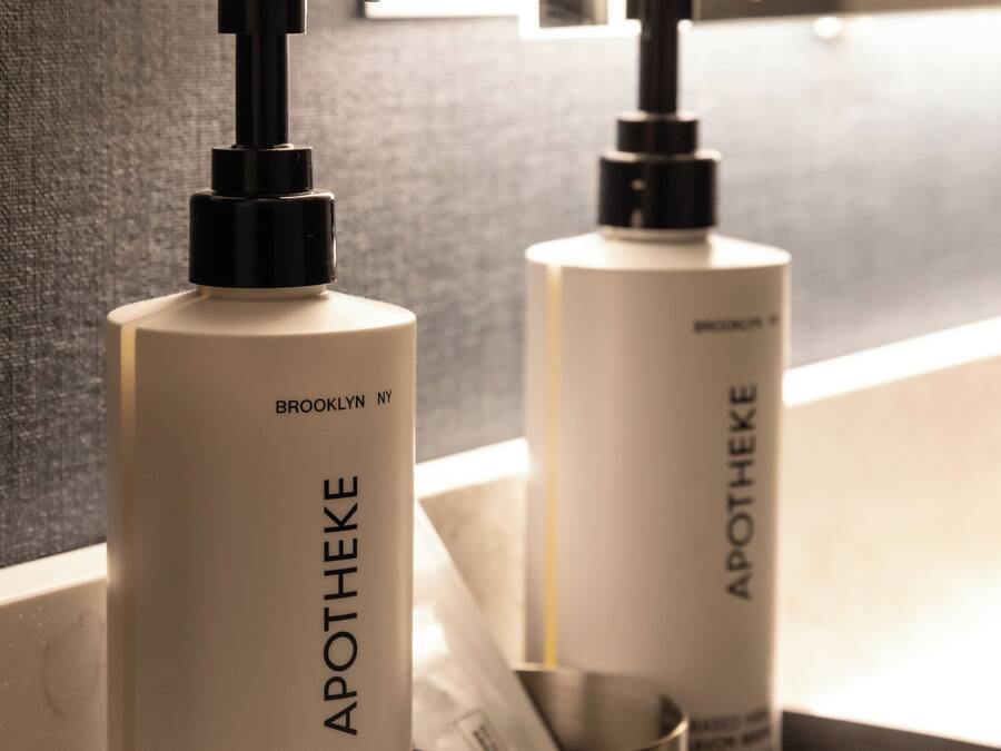 Dois frascos de loção vegetal Apotheke sobre um suporte.