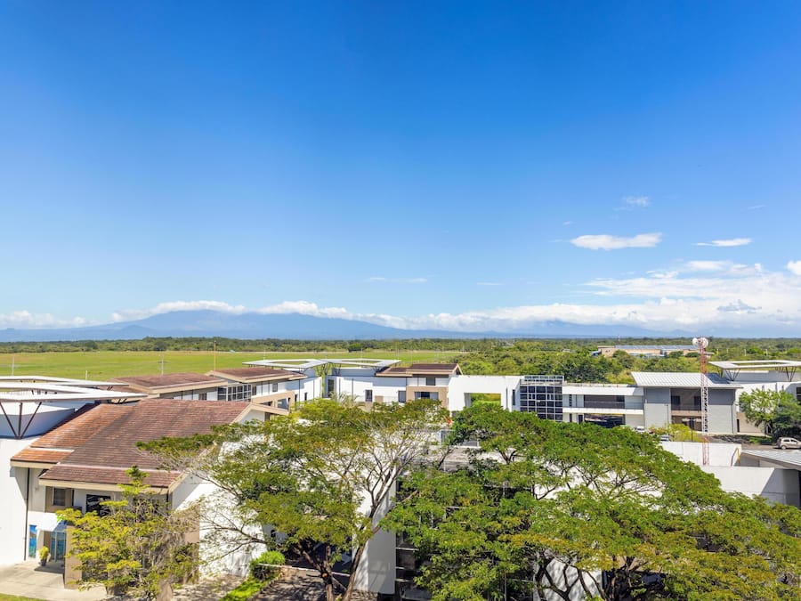 Zona residencial com casas modernas, céu azul límpido e montanhas ao longe.
