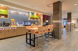 Um restaurante moderno com um balcão extenso, diversas áreas de estar e uma variedade de estações de comida e bebidas.