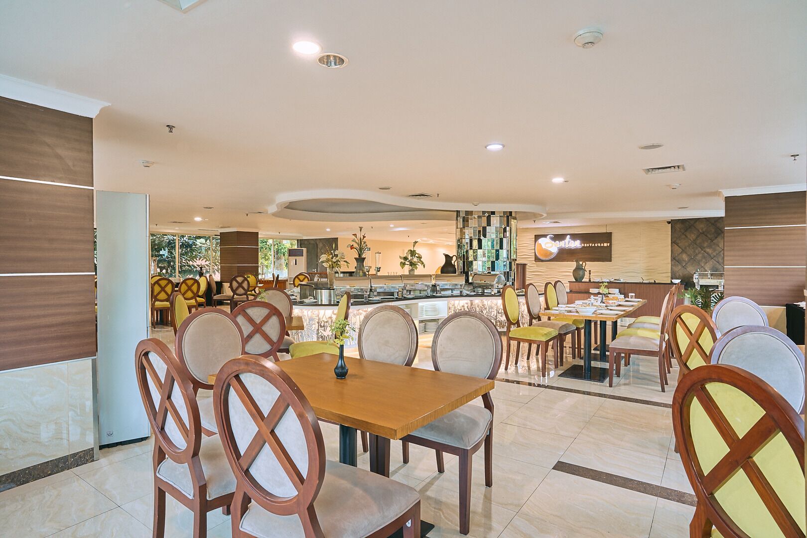 Um restaurante moderno com mesas e cadeiras de madeira, um balcão central e vista para o exterior.