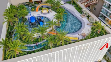 Uma área de piscina no terraço com várias fontes, palmeiras e espreguiçadeiras.