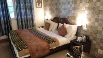 Quarto de hotel com uma cama, mesa de cabeceira, cafeteira e um quadro na parede.