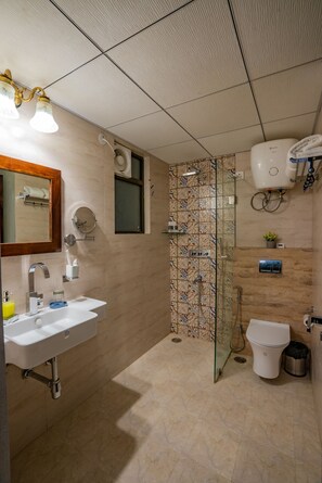 Uma casa de banho moderna com lavatório, espelho, chuveiro e sanita.