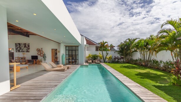 Uma casa moderna com piscina, deck de madeira e gramado bem cuidado.