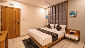Quarto com cama, mesa de cabeceira e ventoinha no teto.