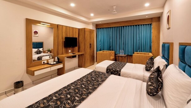Quarto de hotel com duas camas, uma escrivaninha, televisão e banheiro.