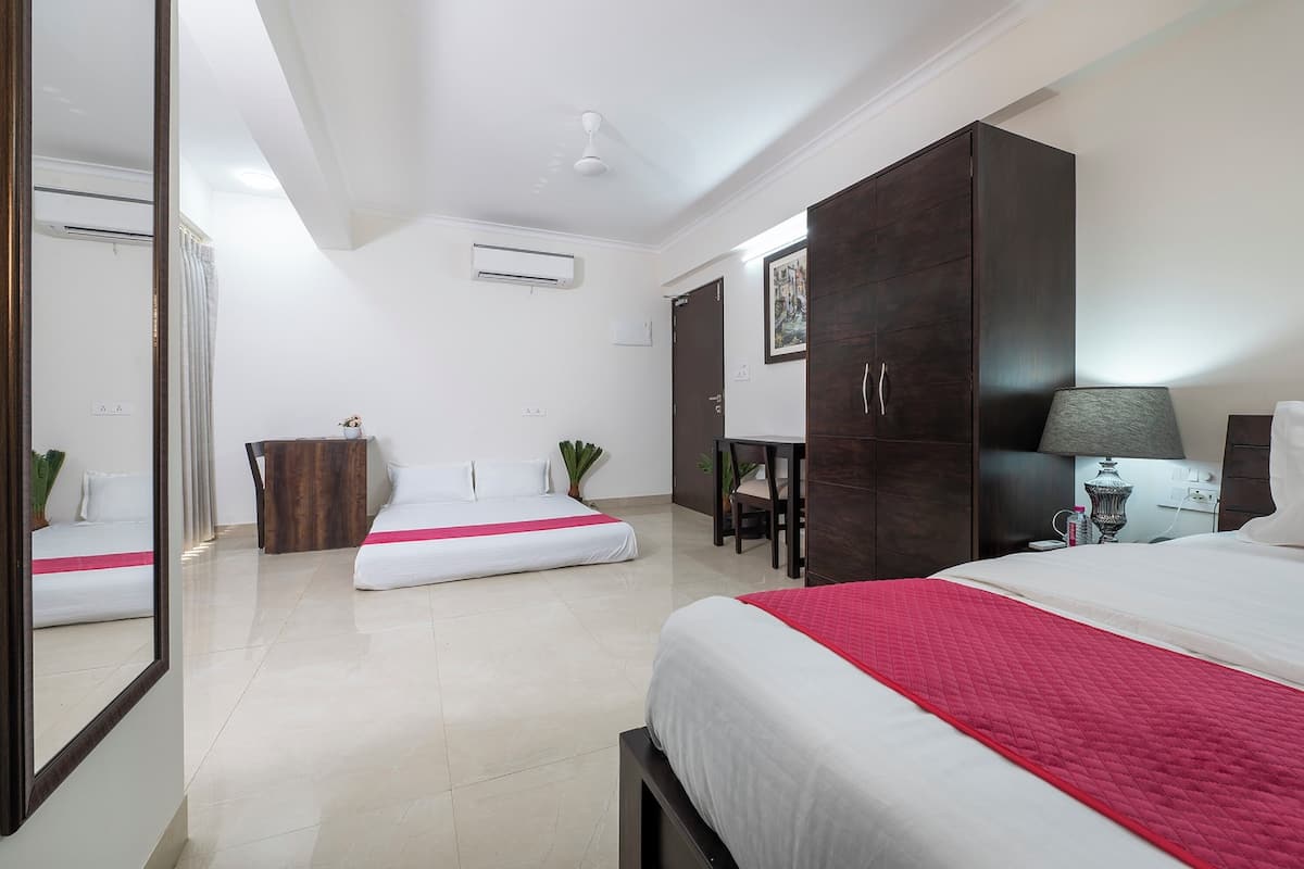 Quarto de hotel com cama, secretária, guarda-roupa e espelho.