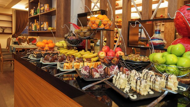 Buffet com diversos alimentos, incluindo frutas, sobremesas e bebidas.