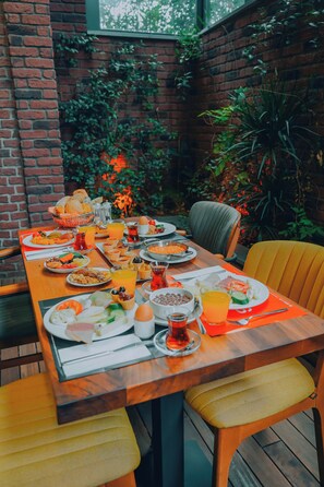 Uma mesa de jantar de madeira posta com pratos, copos e diversos alimentos.