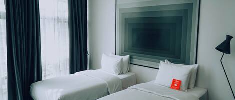 Quarto de hotel com duas camas, um quadro abstrato grande na parede e um abajur de chão preto.
