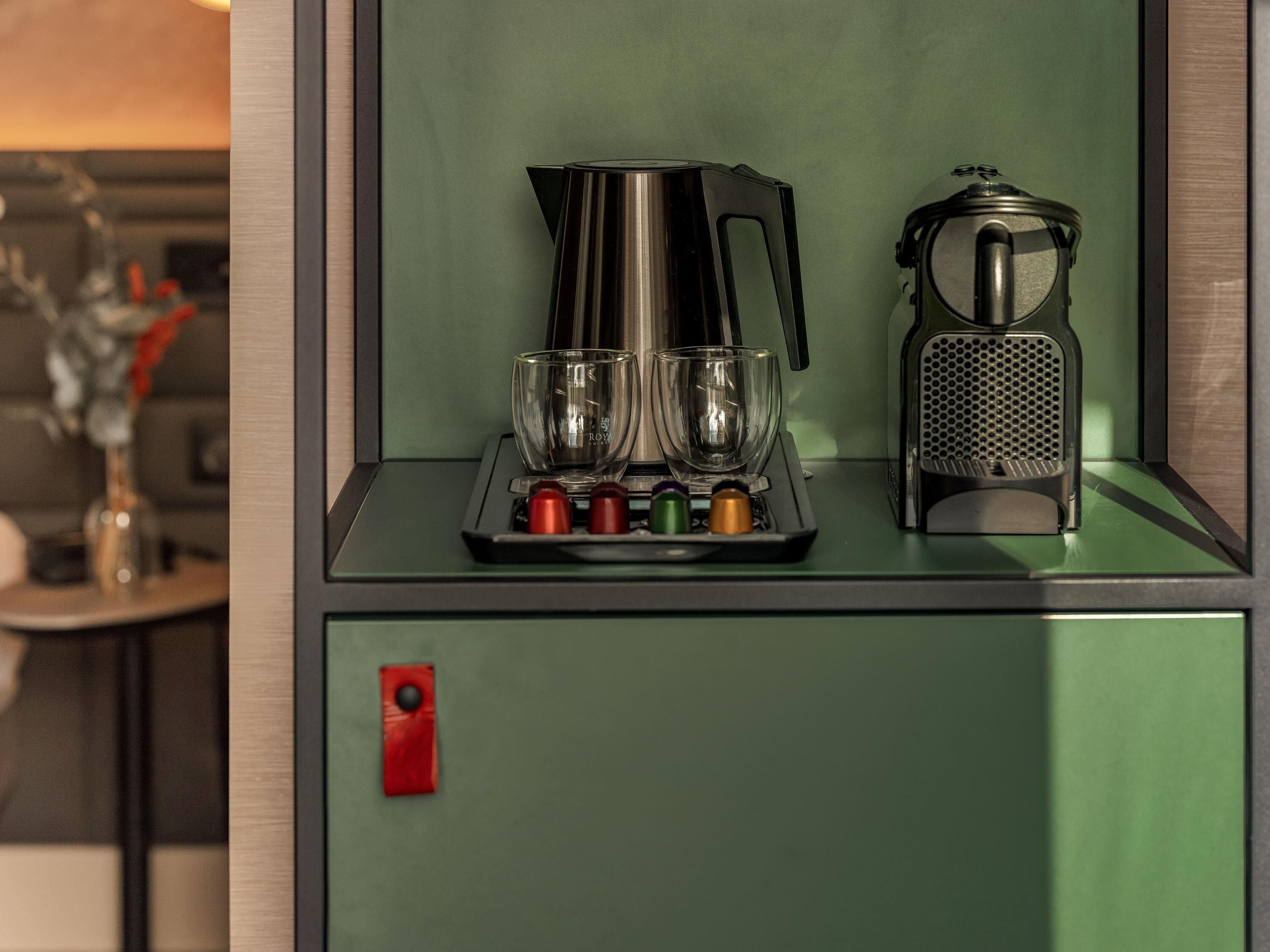 Uma cozinha compacta com cafeteira, dois copos e um ralador.