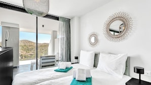 Quarto de hotel moderno com duas camas, uma janela grande com vista para uma paisagem montanhosa e arte decorativa na parede.