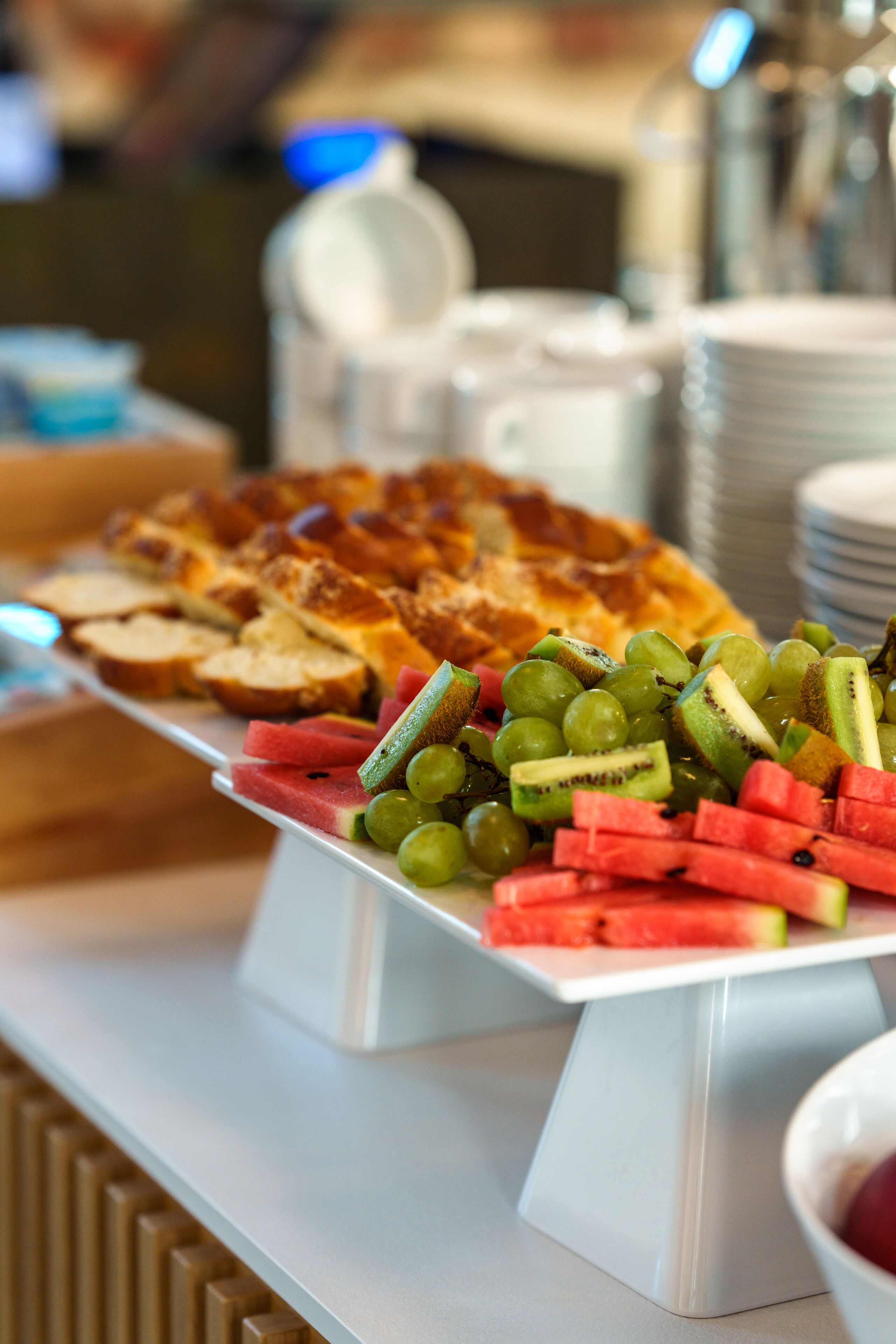 Buffet com pão fatiado, uvas, melancia e kiwi.