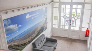 Escada que leva a um patamar com um sofá cinza e um cartaz dos Apartamentos Bridlington Bay.