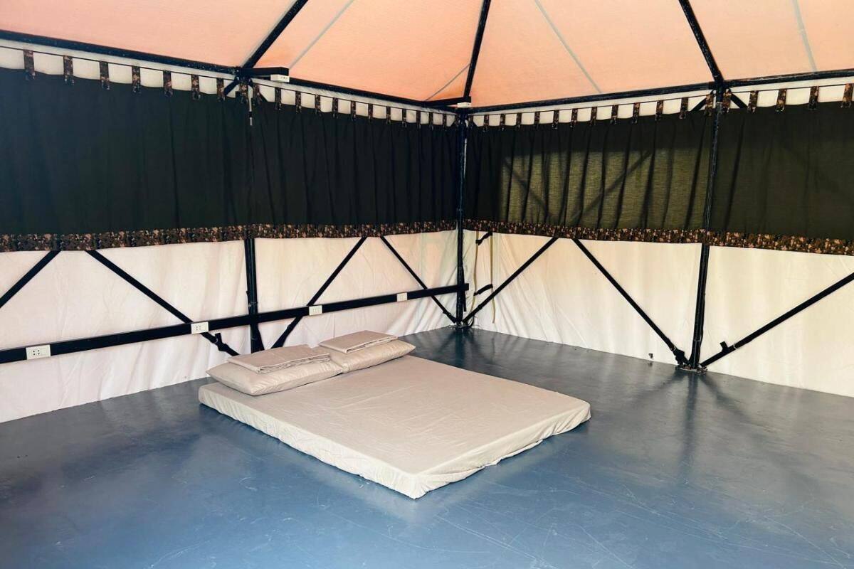 Uma tenda com uma cama, cortinas em preto e branco e um chão azul.
