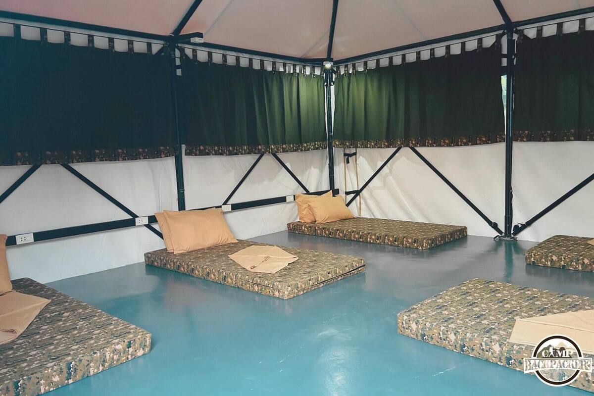 Uma tenda com quatro áreas de dormir, cada uma com colchão e almofadas.