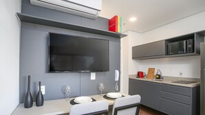Uma cozinha moderna com televisão de tela plana, micro-ondas e área de jantar com mesa posta para dois.
