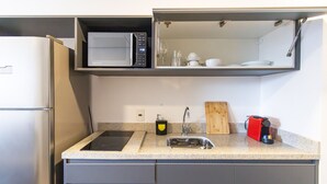 Uma cozinha compacta com micro-ondas embutido, pia e tábua de corte.