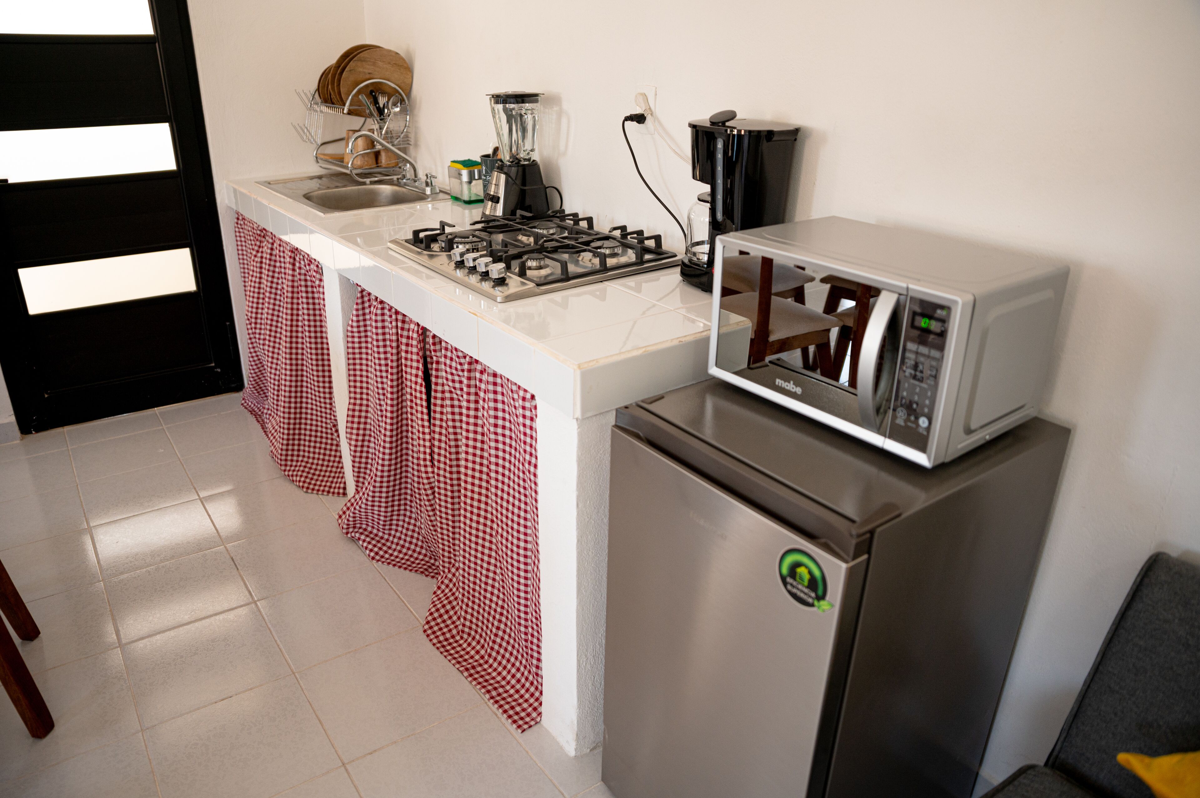 Cozinha compacta com fogão a gás, micro-ondas e geladeira.