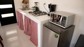 Cozinha compacta com fogão a gás, micro-ondas e geladeira.