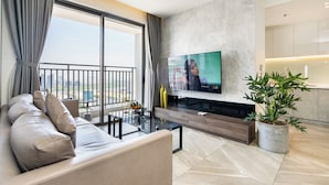 Uma sala de estar moderna com um sofá, uma televisão de tela plana, uma mesa de centro de vidro e um vaso com planta.