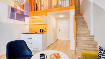 Um apartamento moderno com cozinha, sala de jantar e escada.