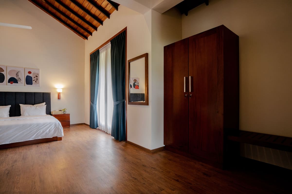 Quarto com cama, piso de madeira, guarda-roupa e mesa de cabeceira.