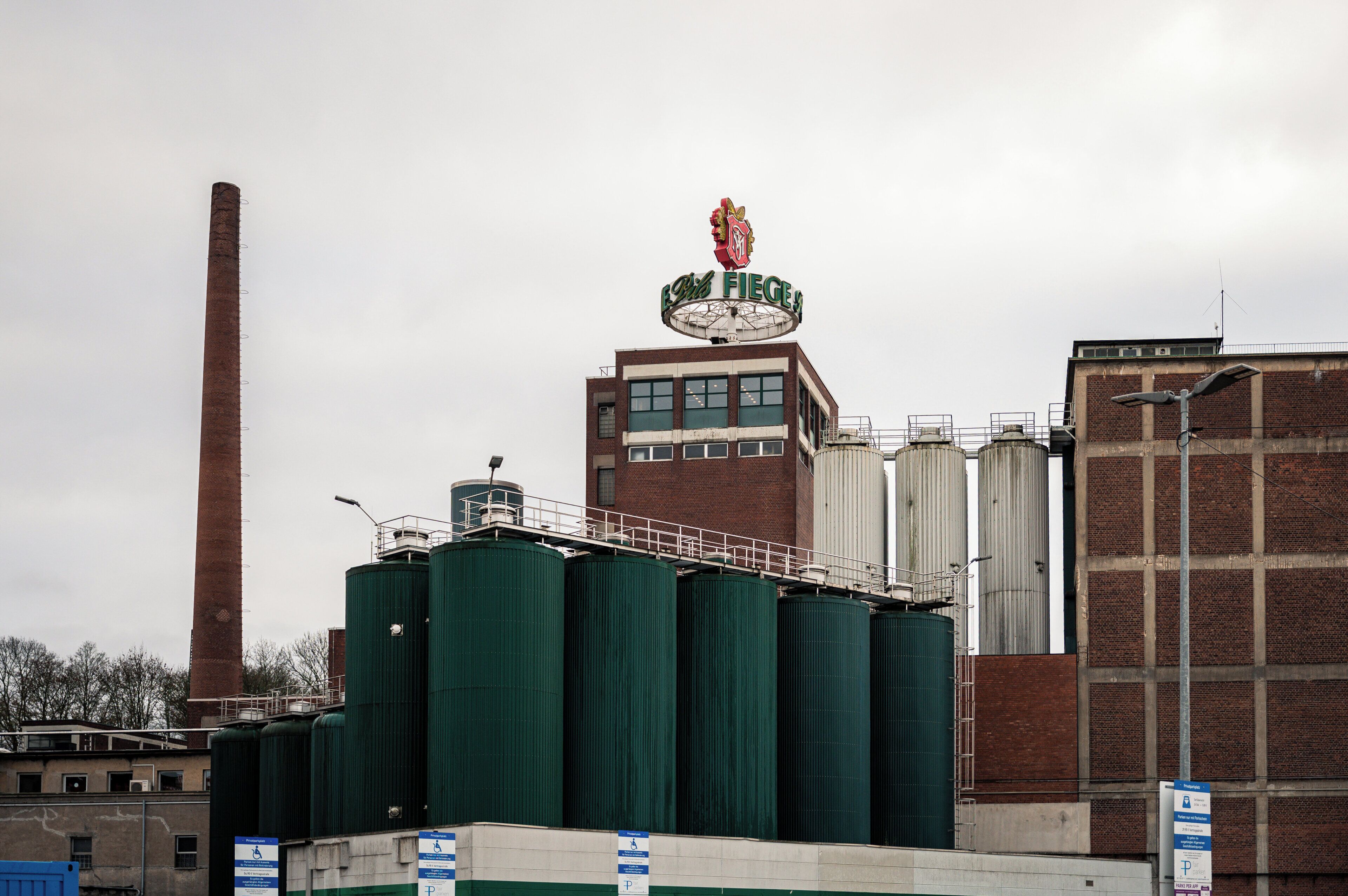 Um edifício com uma placa de destaque indicando 'Rib Fiege' e vários tanques de armazenamento verdes grandes.