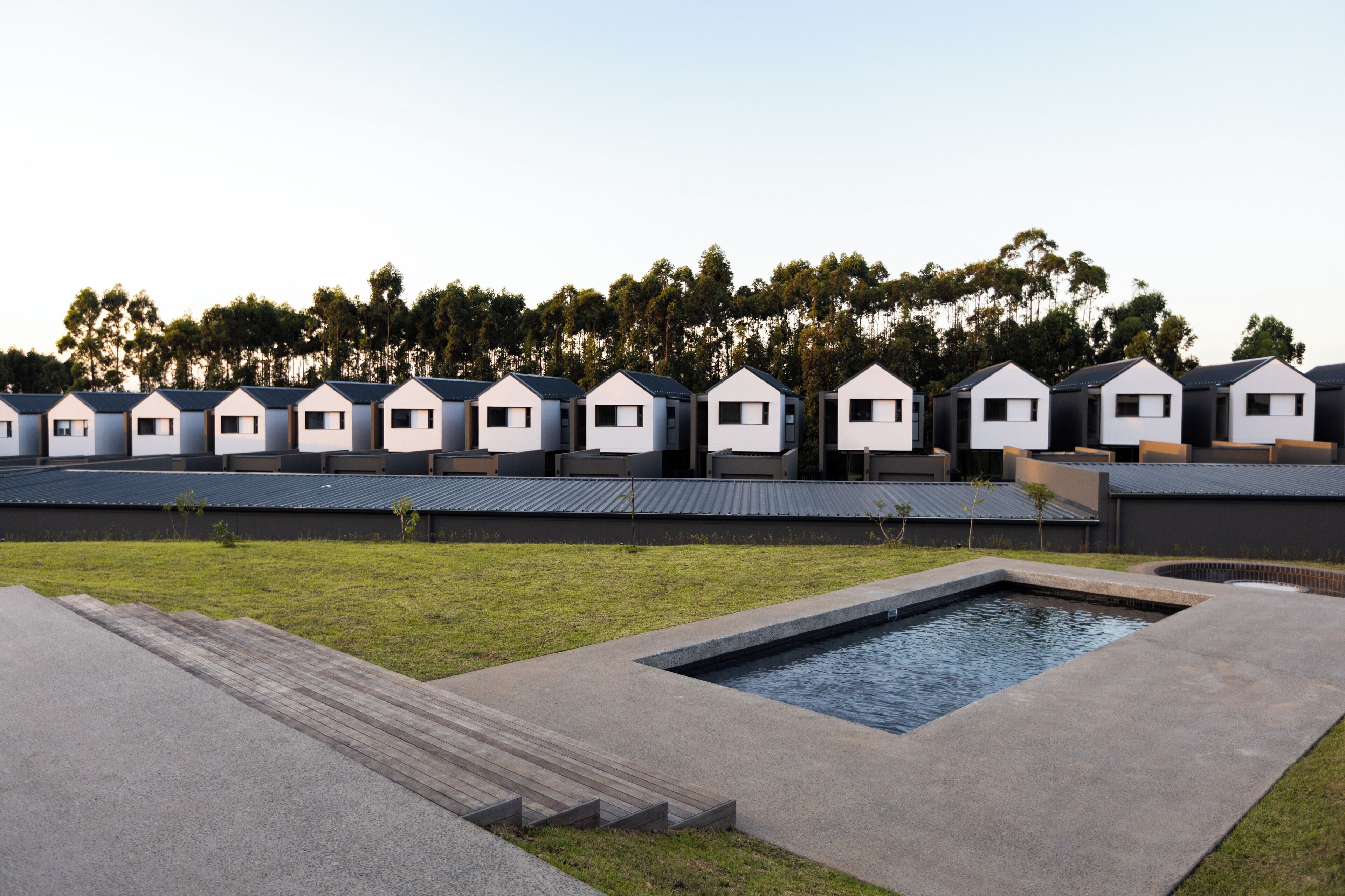 Fileira de cabines modernas e padronizadas, com uma piscina em primeiro plano.