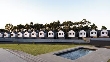 Fileira de cabines modernas e padronizadas, com uma piscina em primeiro plano.