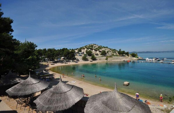 Na praia, guarda-sóis, prática de vôlei de praia