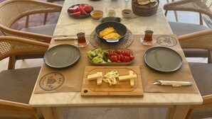 Mesa posta com pratos, talheres e alimentos em um ambiente bem iluminado por luz natural.