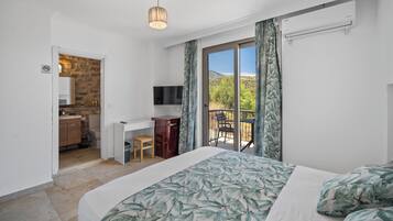 Quarto com cama, escrivaninha, televisão e varanda com vista para o exterior.