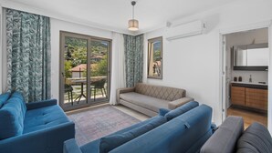 Uma sala de estar moderna com um conjunto de sofá azul, um sofá bege e um espaço de jantar com mesa e cadeiras.