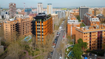 Um edifício alto com vários andares, cercado por outros edifícios e uma rua movimentada.